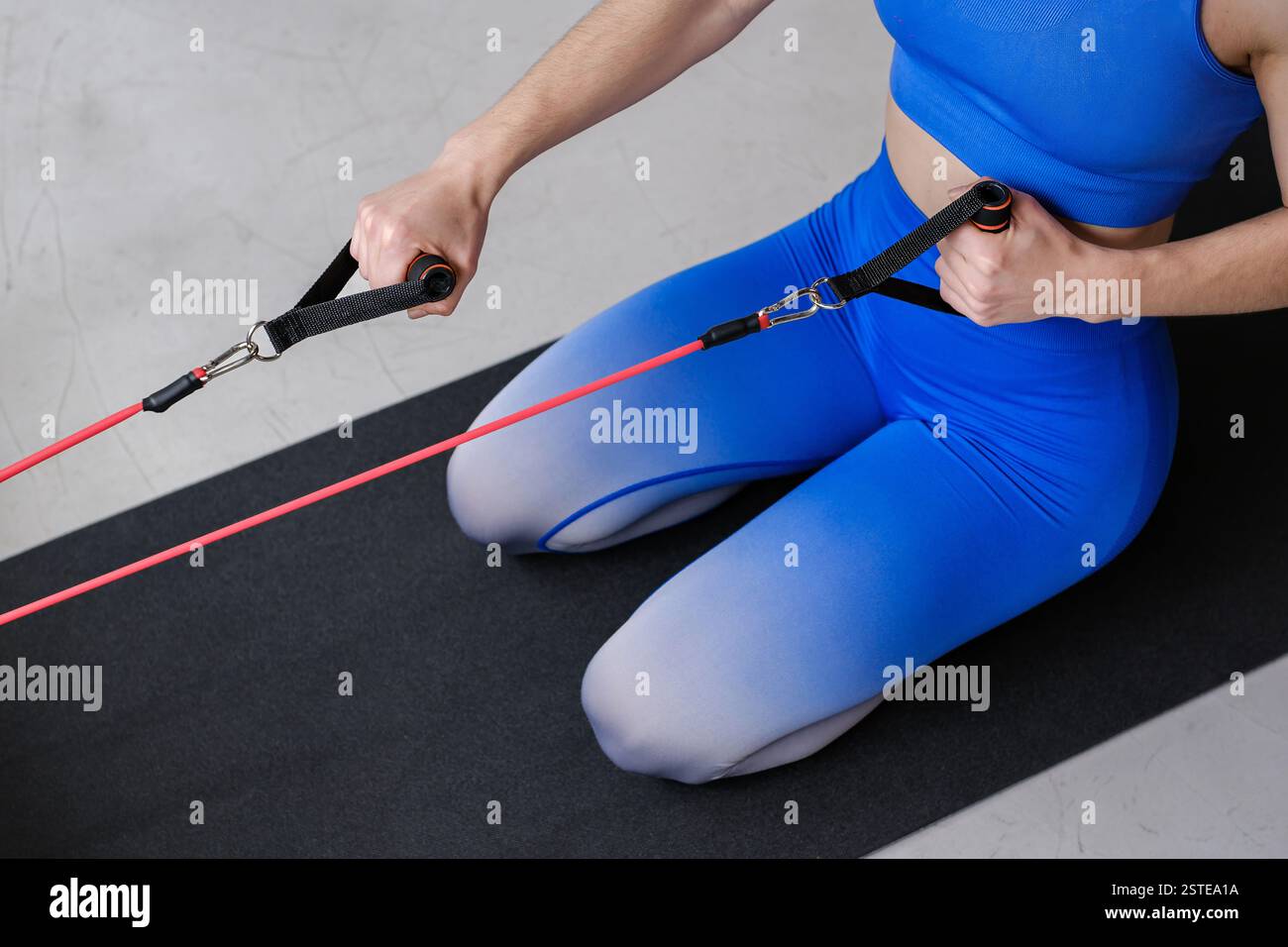 Anonymous engaged woman kneels on a fitness mat, working out with a ...