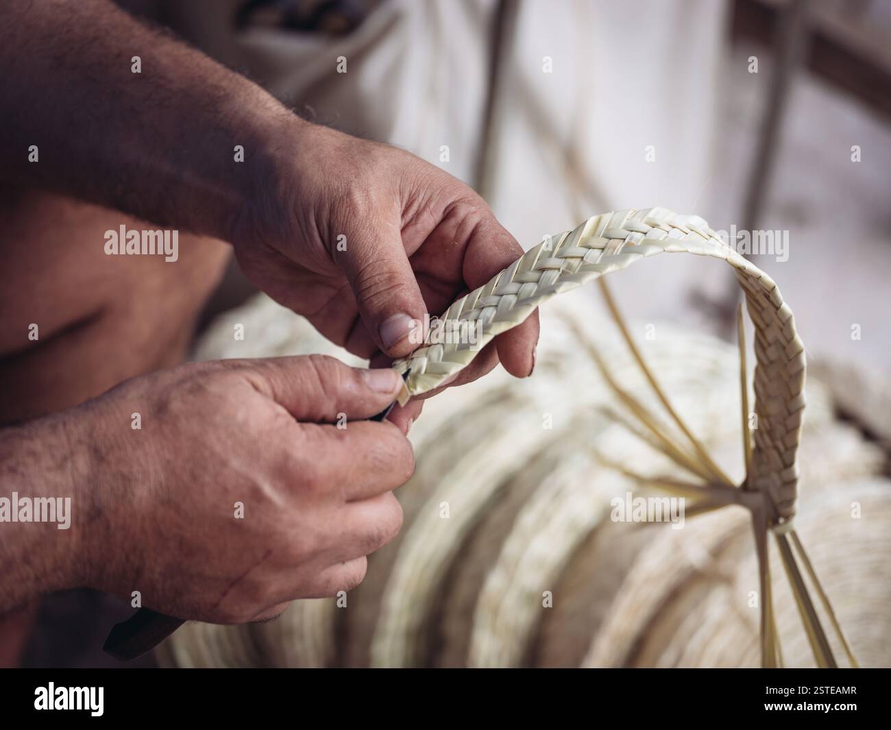 A skilled artisan meticulously weaves a traditional basket using ...