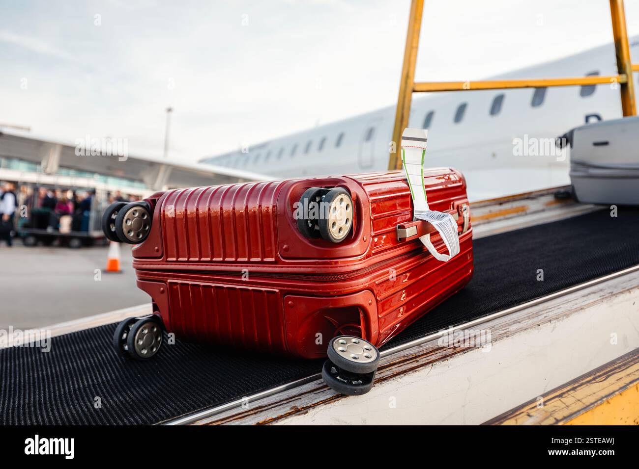 Loading of luggage to airplane. Red suitcase on conveyor belt at ...