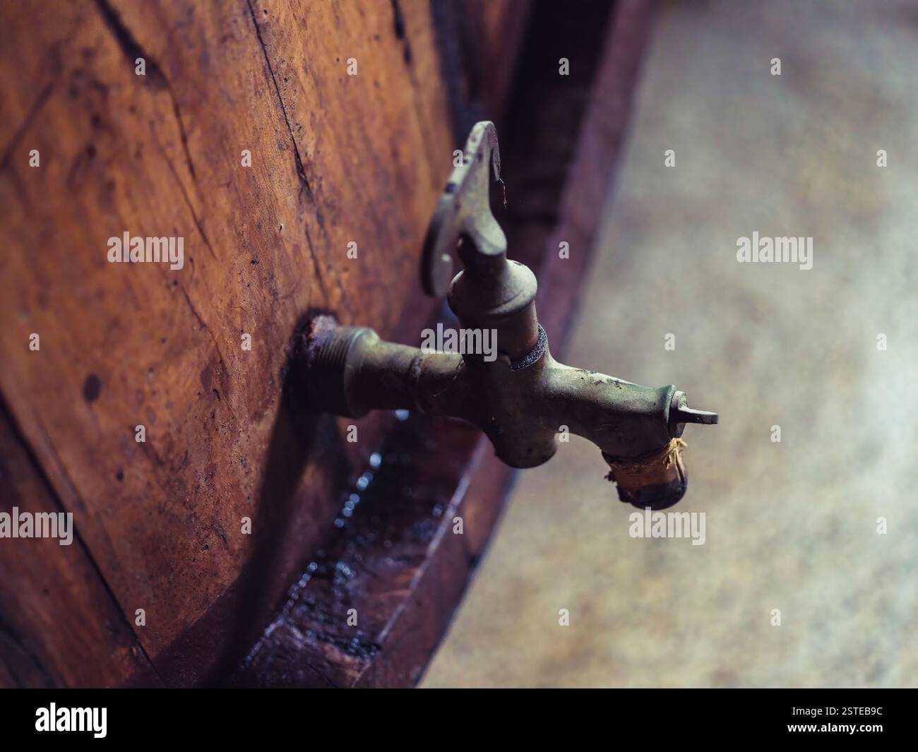 Close-up view of an old, rustic tap attached to a wooden barrel ...