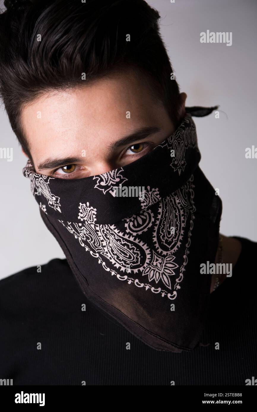 Man with his face hidden behind a bandanna stares balefully at the ...