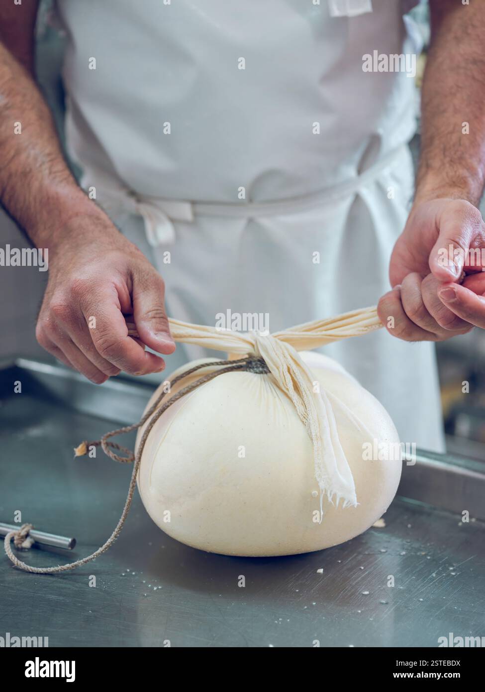 A detailed view of an artisan skillfully tying a round Mahon-Menorca ...