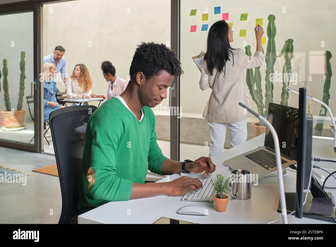 Side view of African American male office worker sitting at table and ...