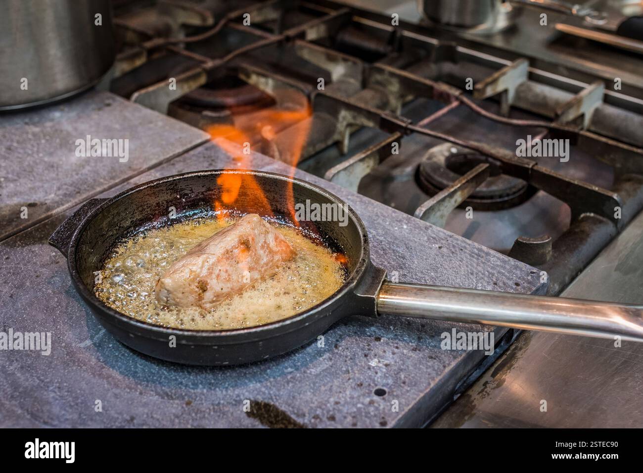 A juicy pork chop sizzles in a cast iron skillet, surrounded by flames ...