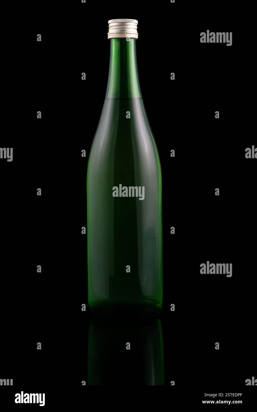 A sleek green glass wine bottle stands upright on a reflective surface ...