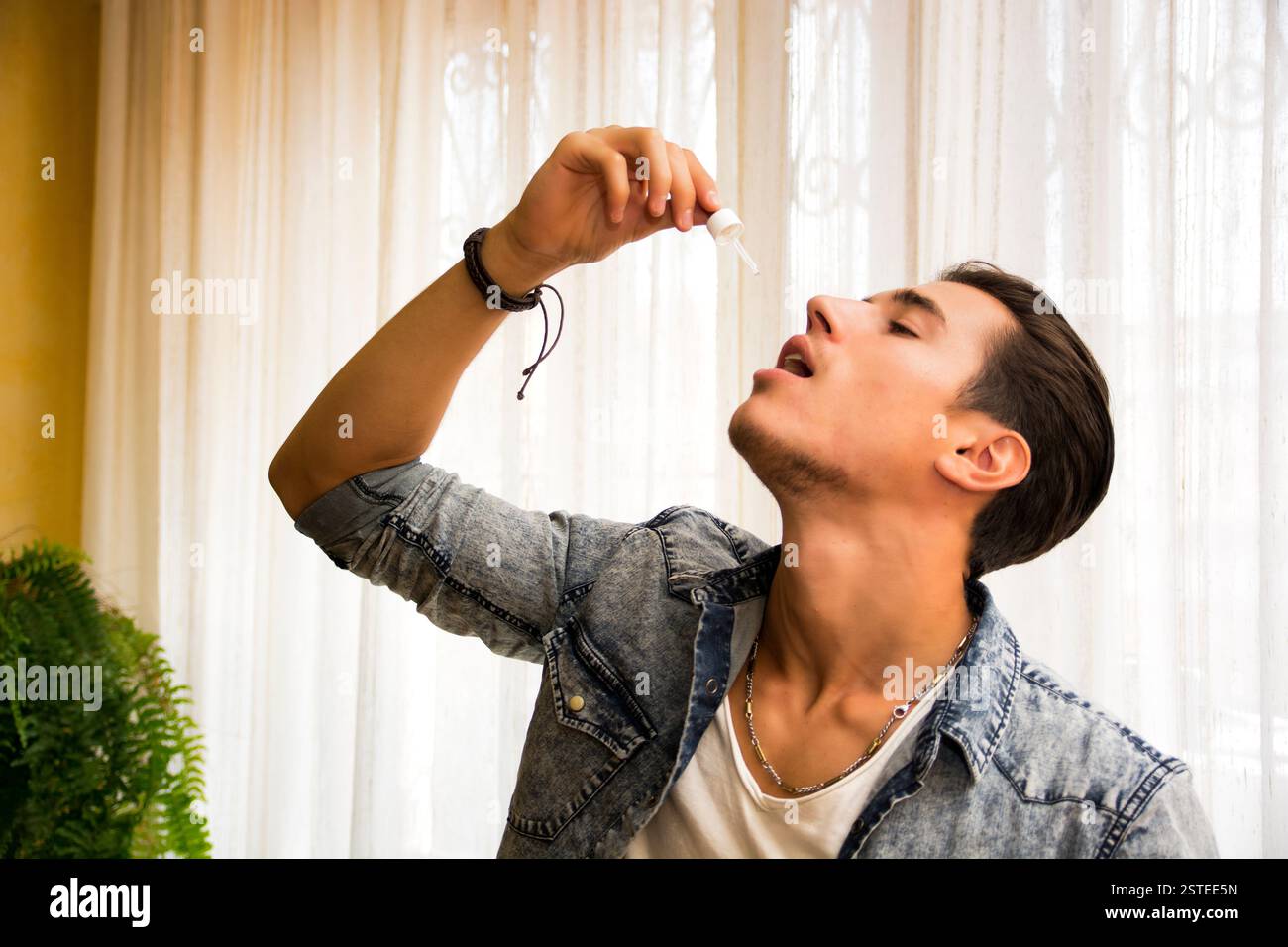 Man Dropping Medicine from Eyedropper into Mouth Stock Photo - Alamy