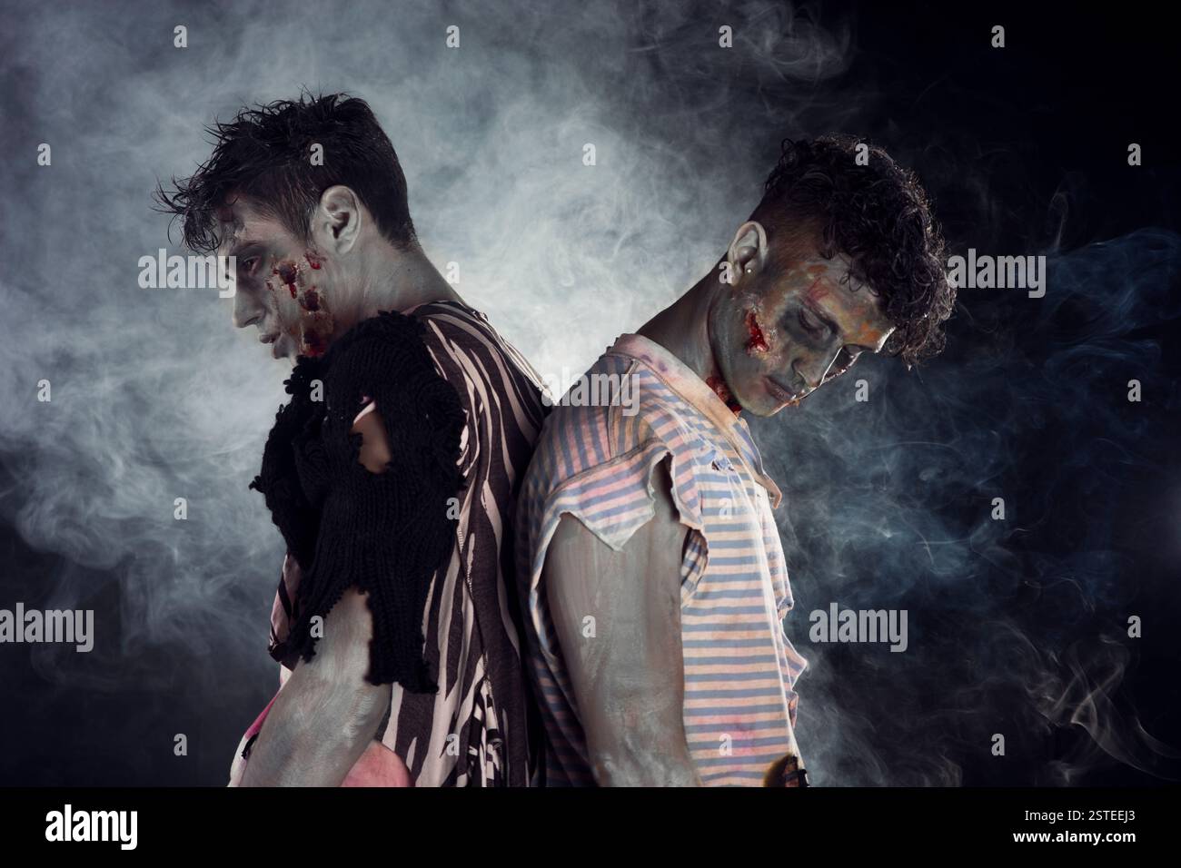 Two male zombies back to back on black smoky background Stock Photo - Alamy
