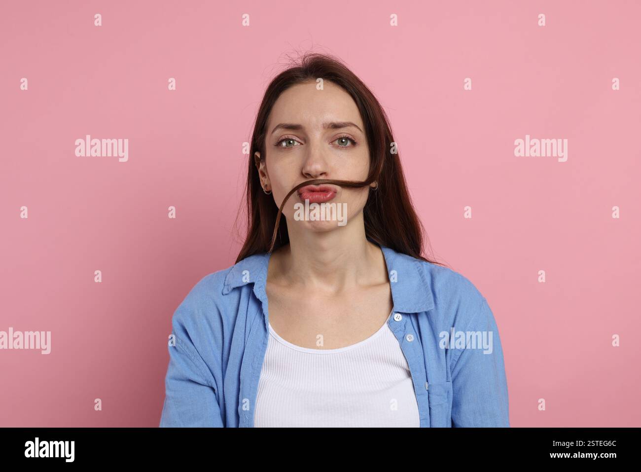 Funny woman making mustache from her hair on pink background Stock Photo - Alamy