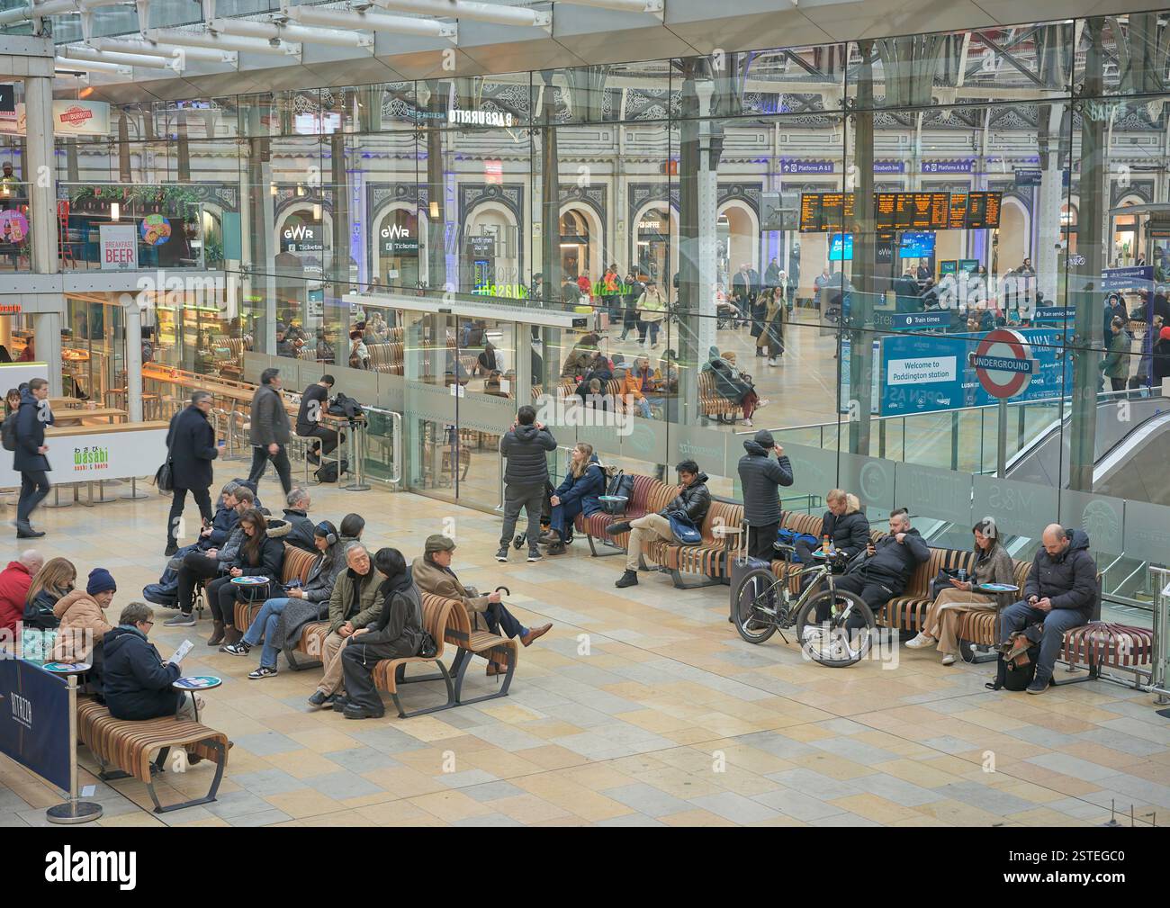 Passengers sit and wait for their trains at Paddington railway station, England, on a winter day ...