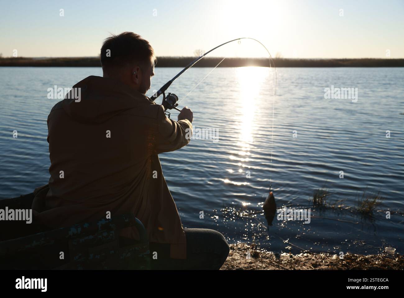 Fisherman catching fish with rod at riverside Stock Photo - Alamy