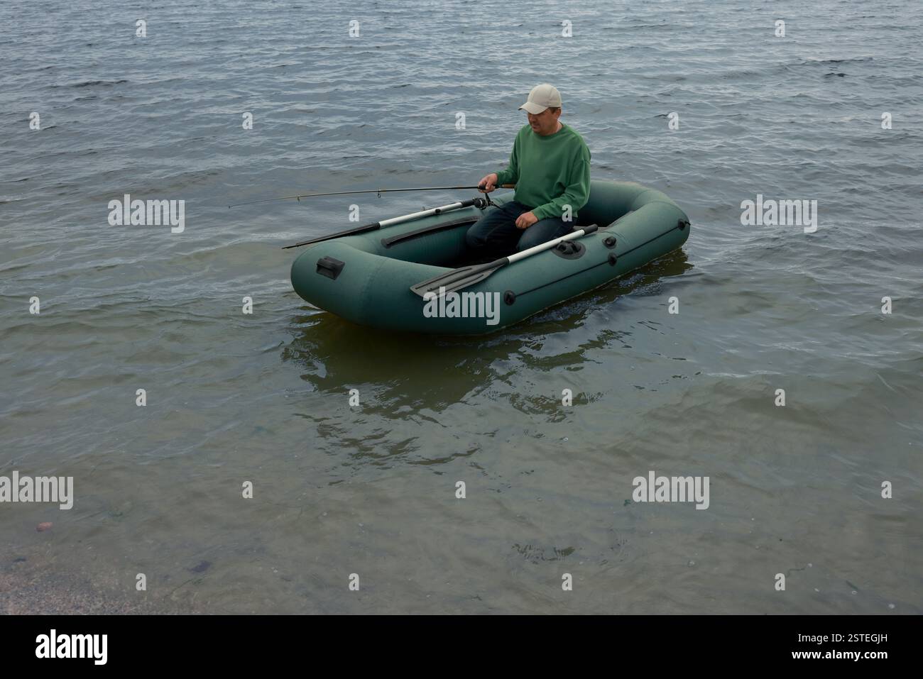Man fishing with rod from inflatable rubber boat on river Stock Photo ...