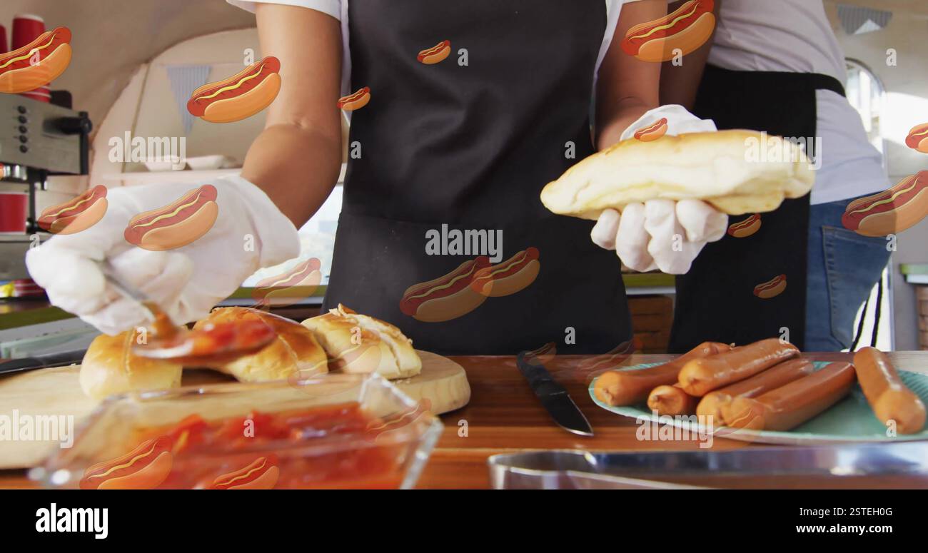 Preparing hot dogs, people in aprons with hot dog image over scene ...
