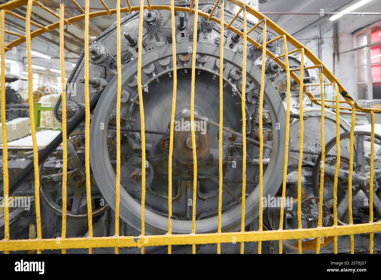 Vintage carding machine in action within a bustling textile factory ...