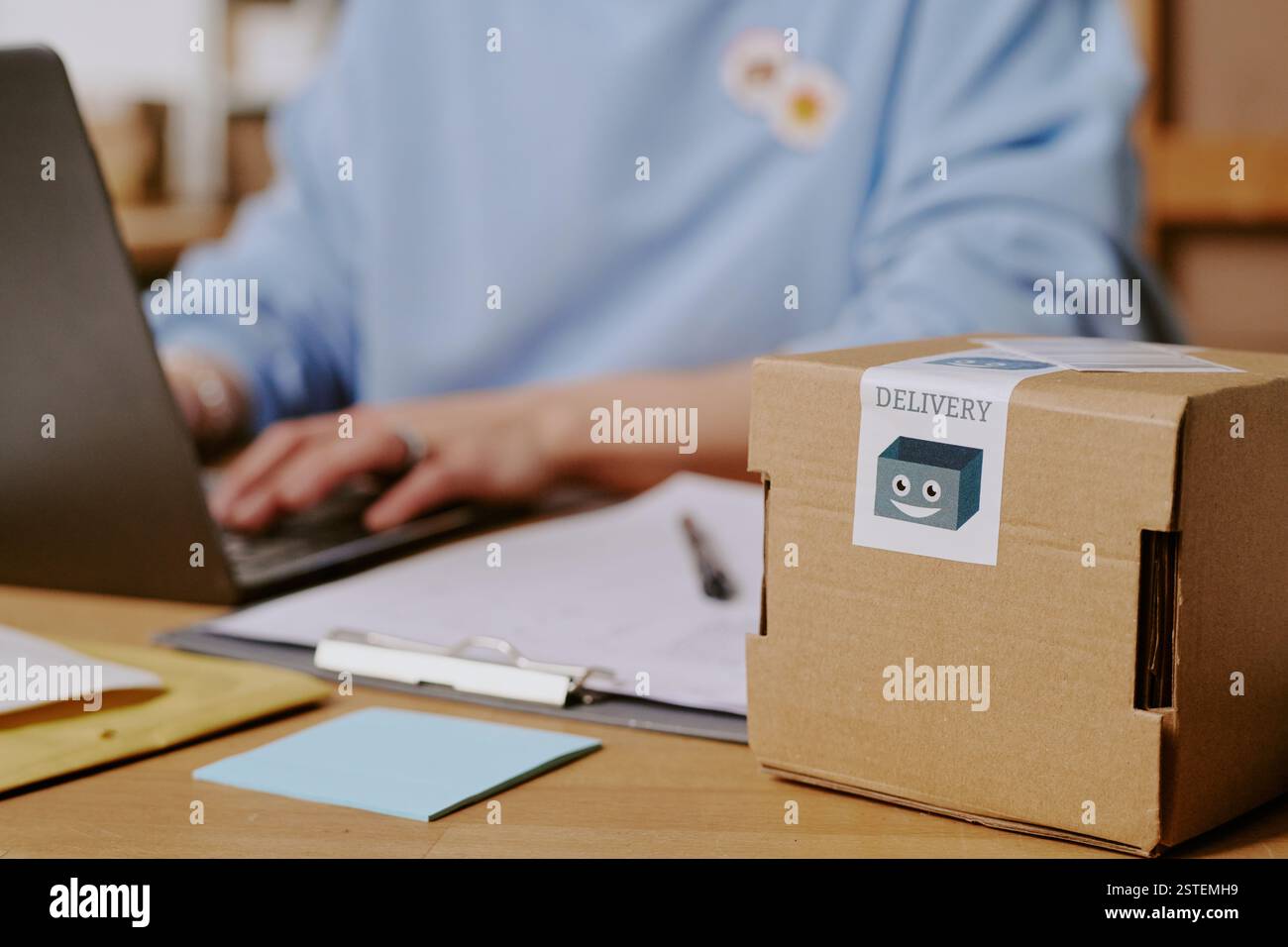 Typing on laptop with delivery box and work documents on desk, showing ...