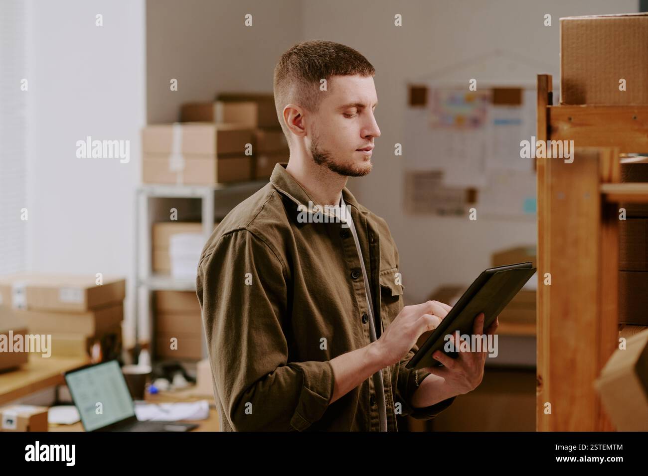 Portrait of young Hispanic man managing inventory in storage room while ...