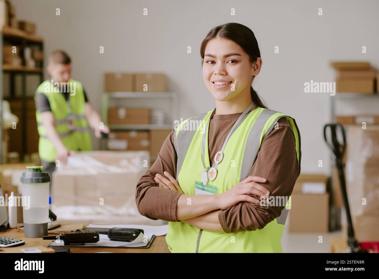 Smiling employee working in a warehouse while unpacking boxes and ...