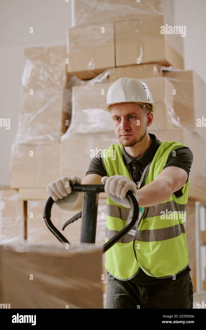 Worker operating forklift in warehouse, stacking boxes packed on wooden ...