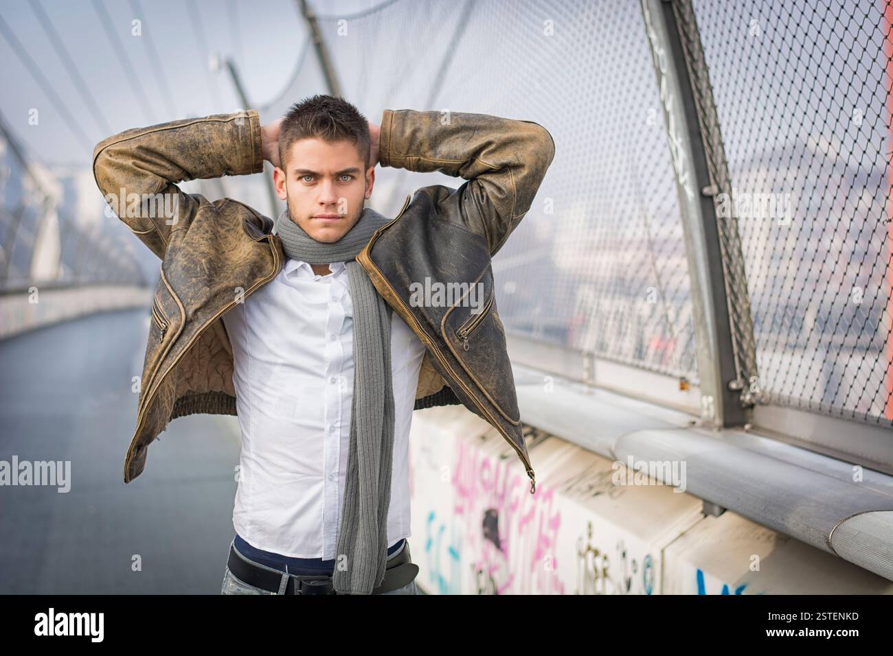 Handsome trendy young man standing on a sidewalk wearing a fashionable ...