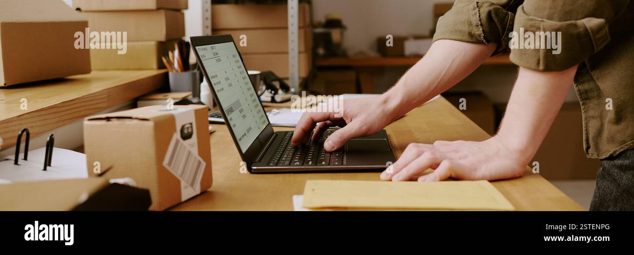 Person organizing tasks at desk, using laptop, cardboard boxes around ...