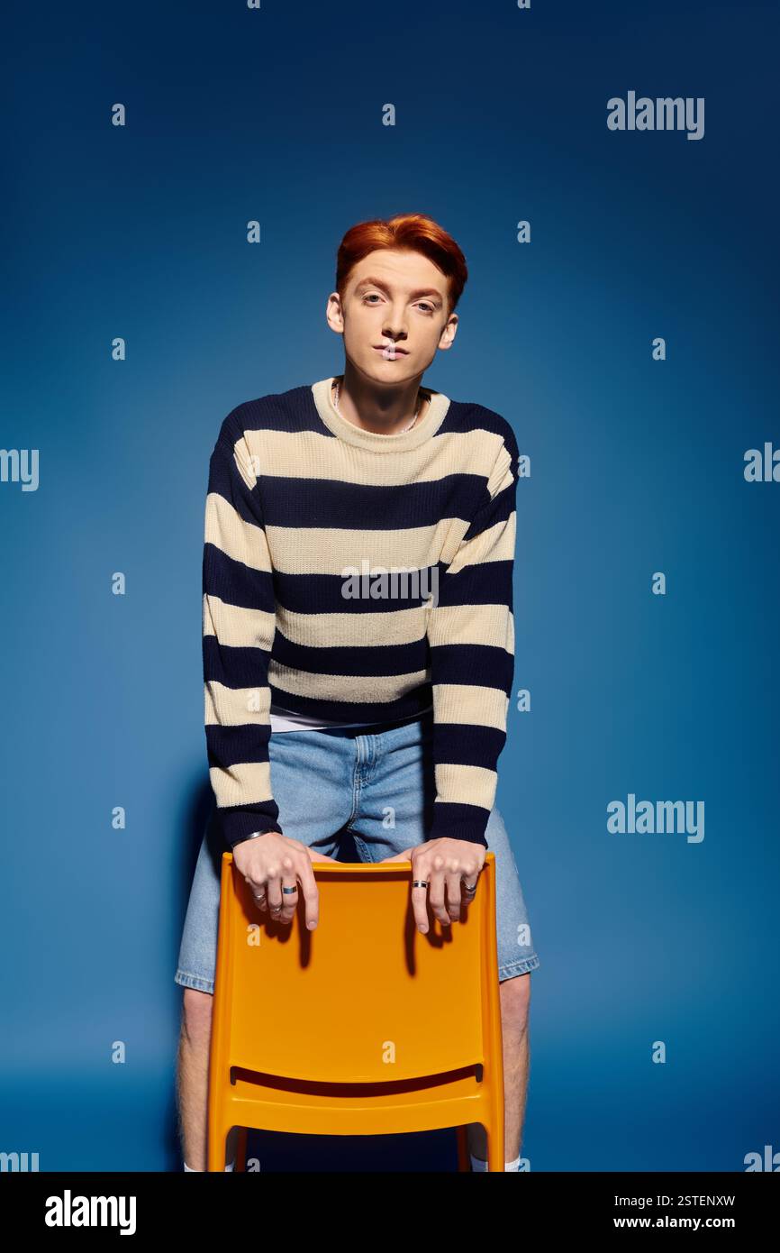 A handsome young man poses with an orange chair, showing deep emotion ...