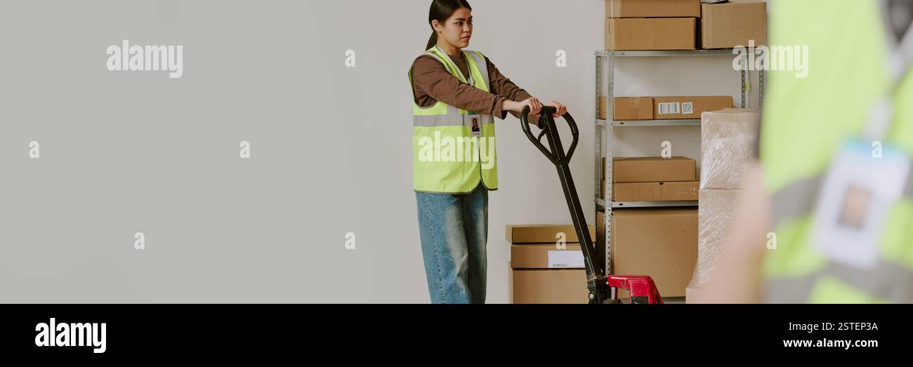 Female worker operating a hand truck in a warehouse environment with ...
