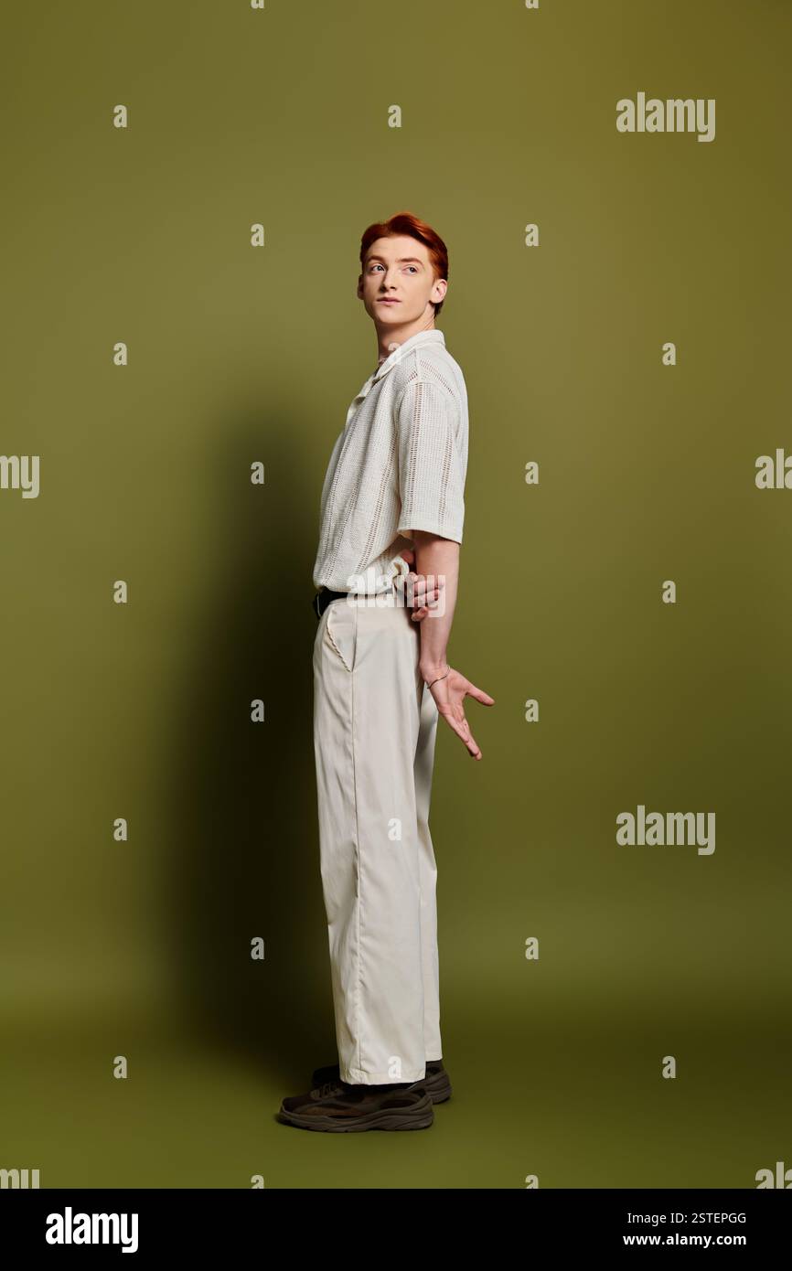 A young, handsome man stands thoughtfully with hands behind his back ...