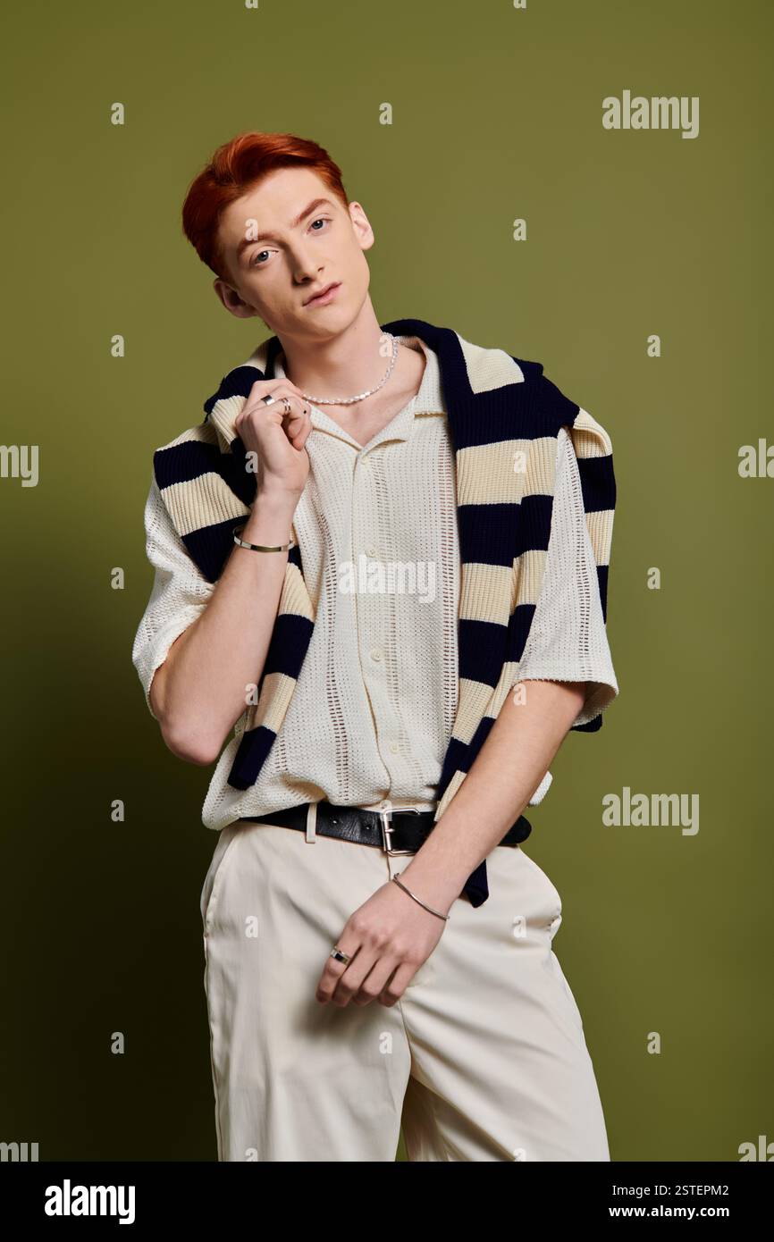 A handsome young man stands confidently, holding a stylish sweater ...