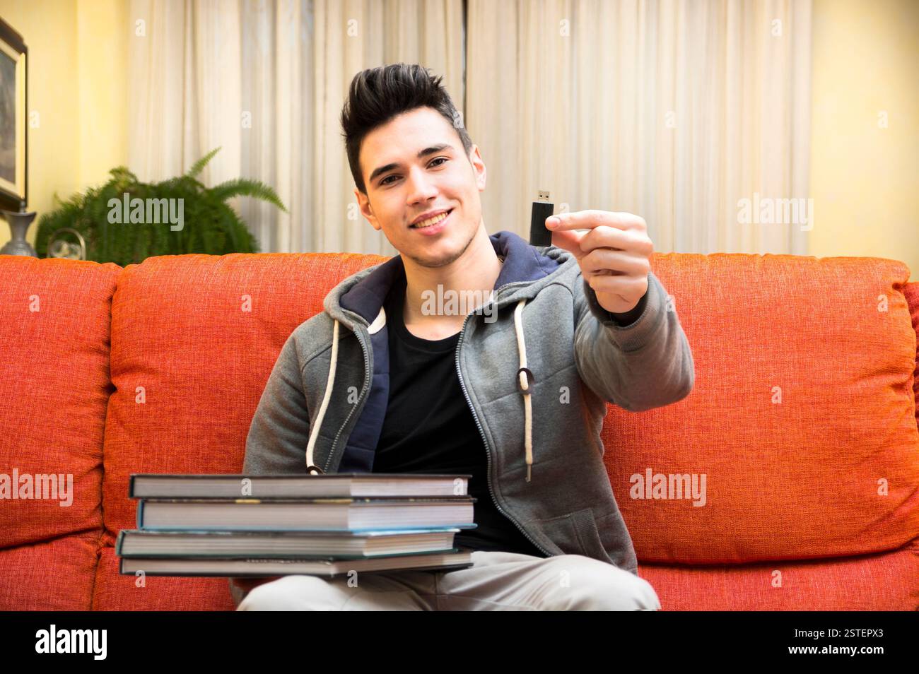 Young man showing difference between USB drive and heavy books Stock ...