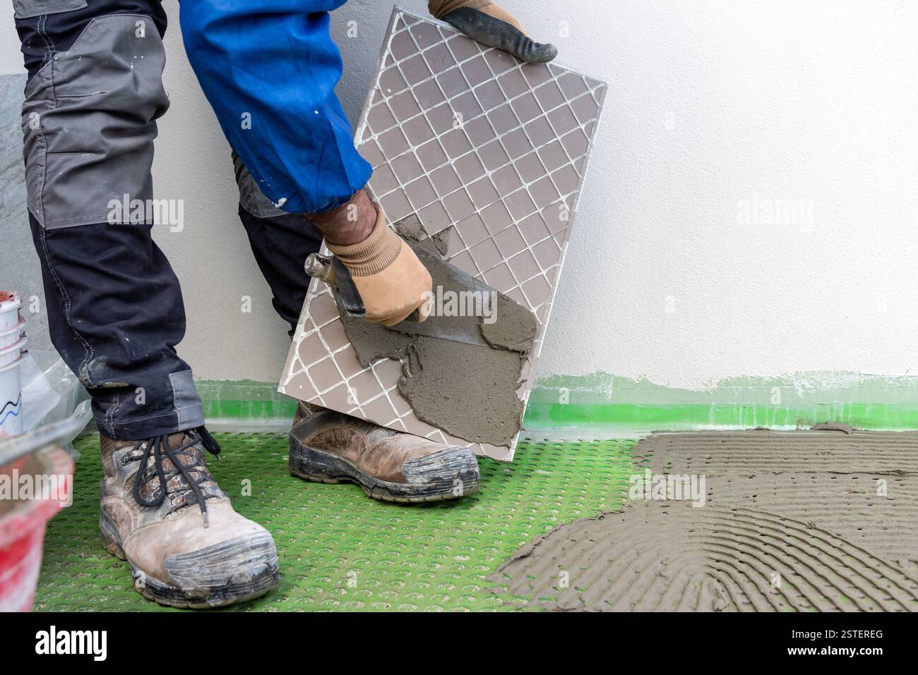 Bricklayer tiler spreads glue on new floor tiles with trowel ...