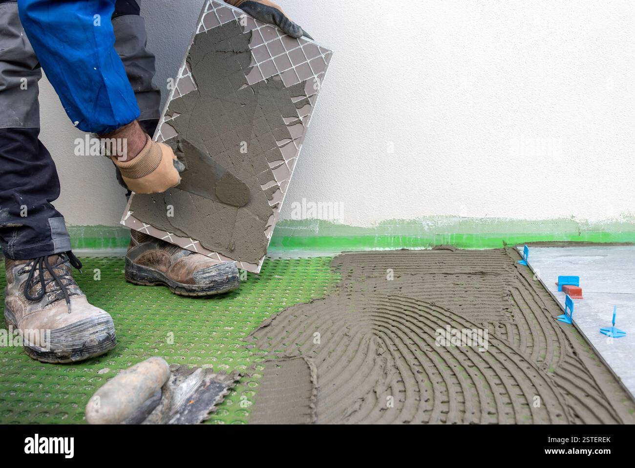 Bricklayer tiler spreads glue on new floor tiles with trowel ...