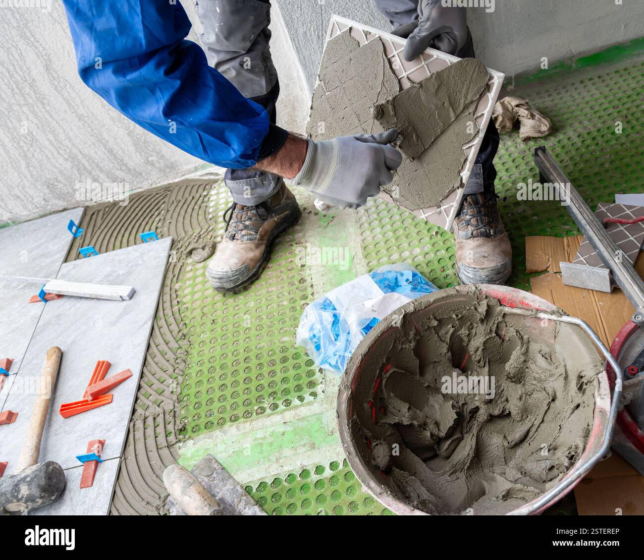 Bricklayer tiler spreads glue on new floor tiles with trowel ...