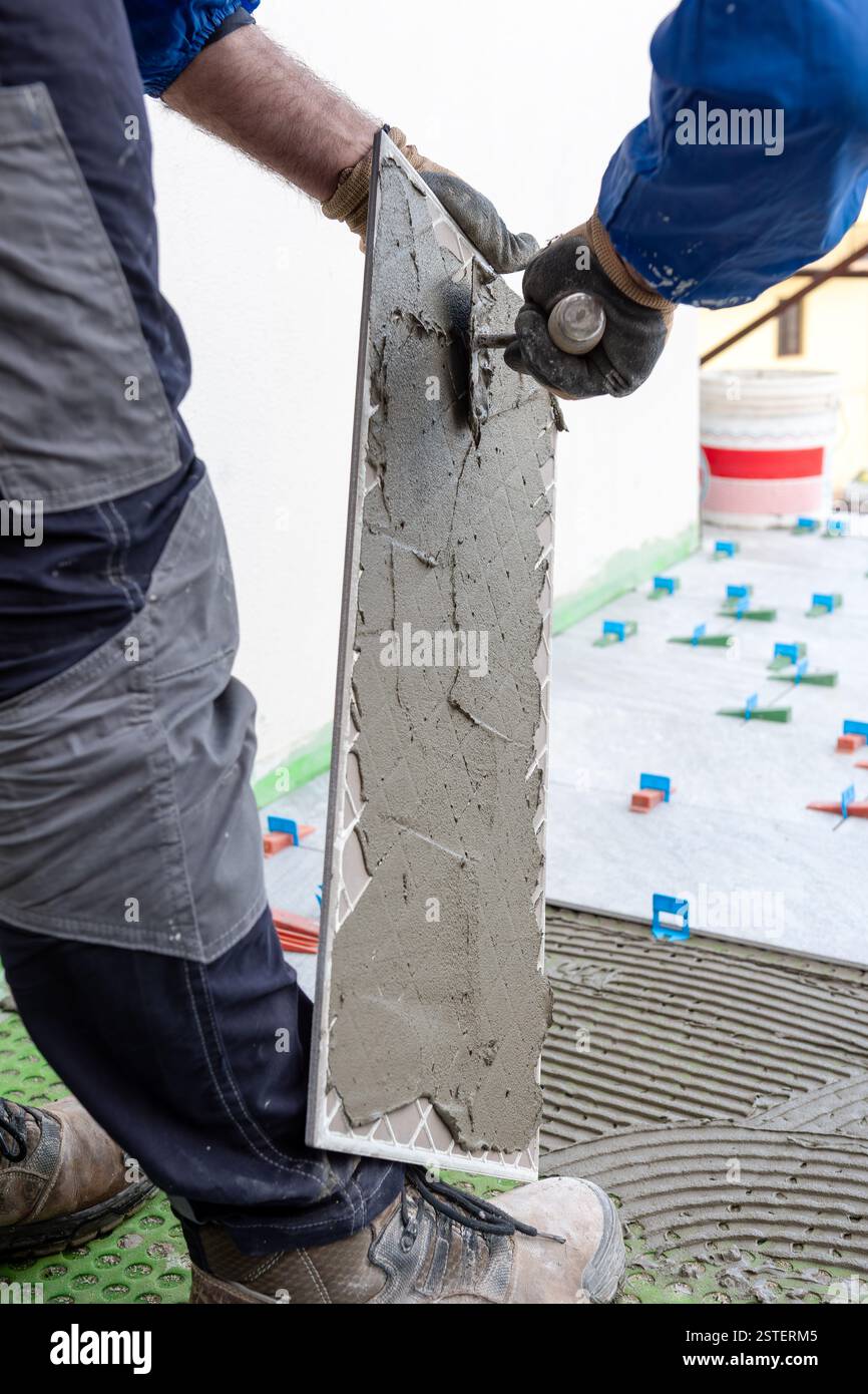 Bricklayer tiler spreads glue on new floor tiles with trowel ...