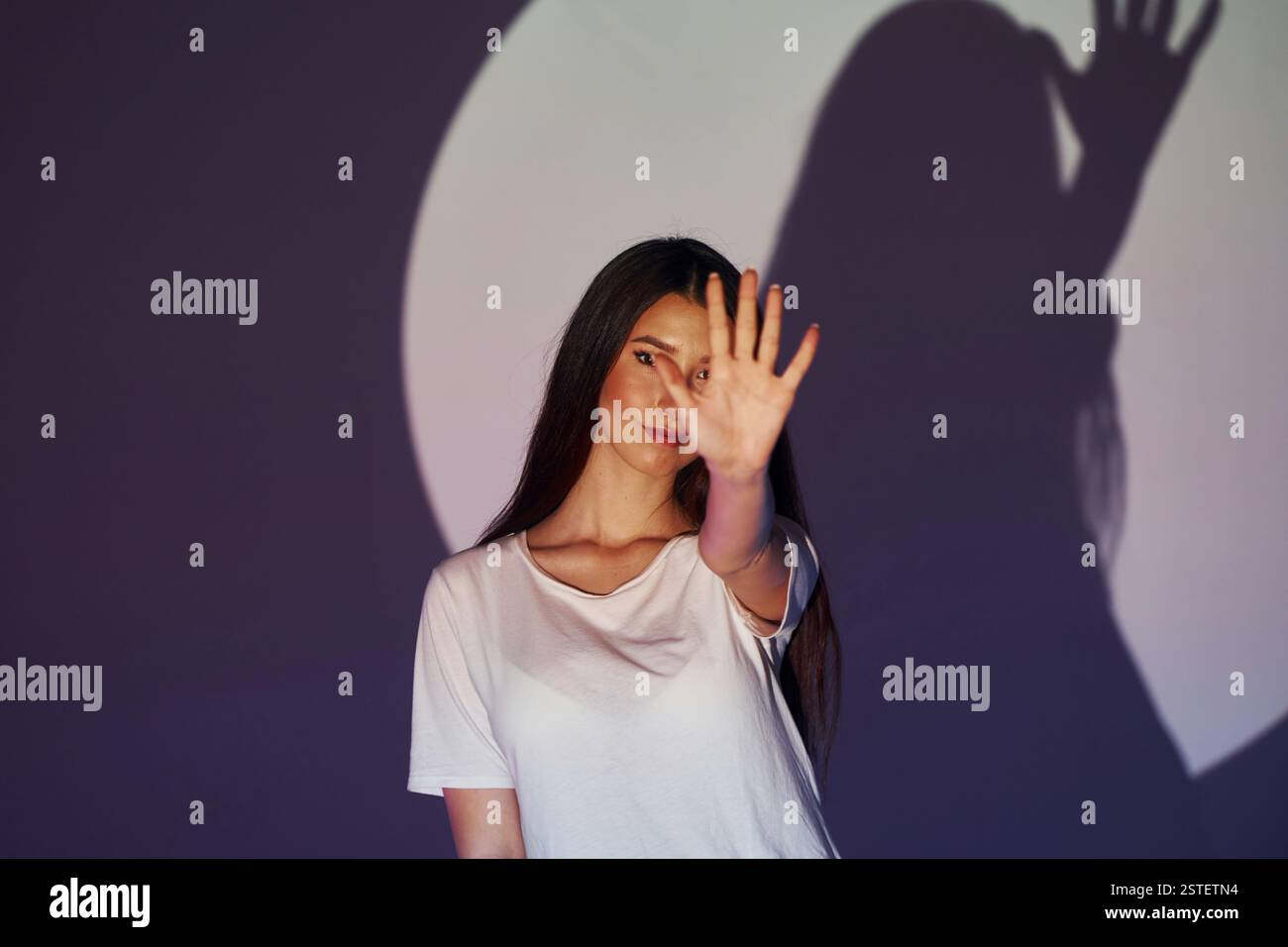 Circle and shadow. Beautiful young woman is in projector neon lights in ...