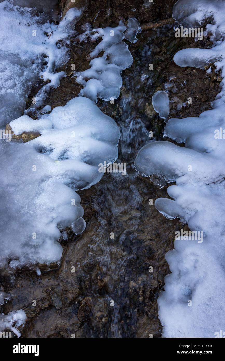 A serene winter scene captures a cold stream flowing through a blanket ...