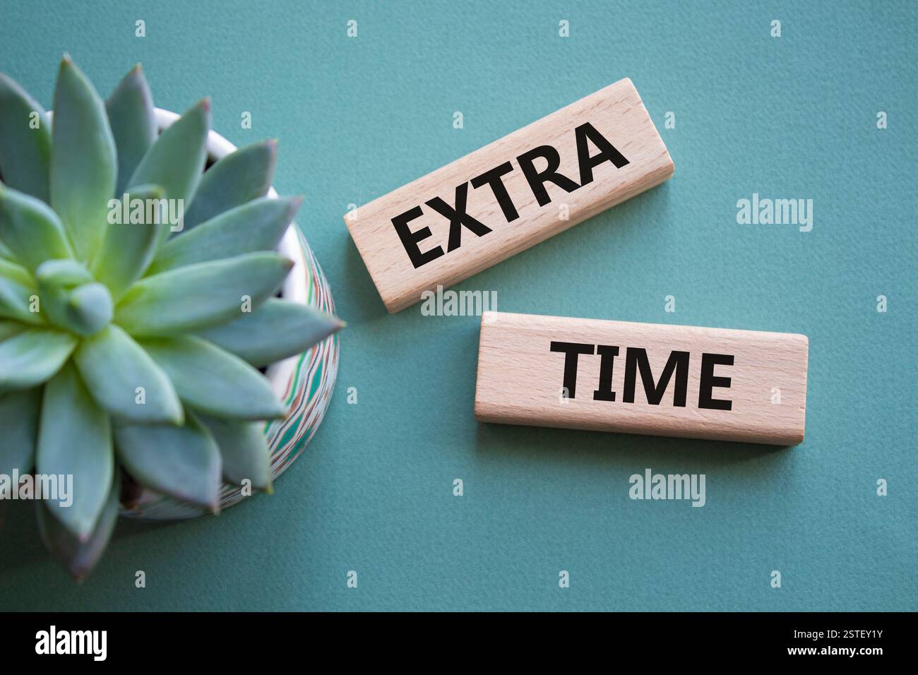 Extra time symbol. Concept word Extra time on wooden blocks. Beautiful grey green background ...