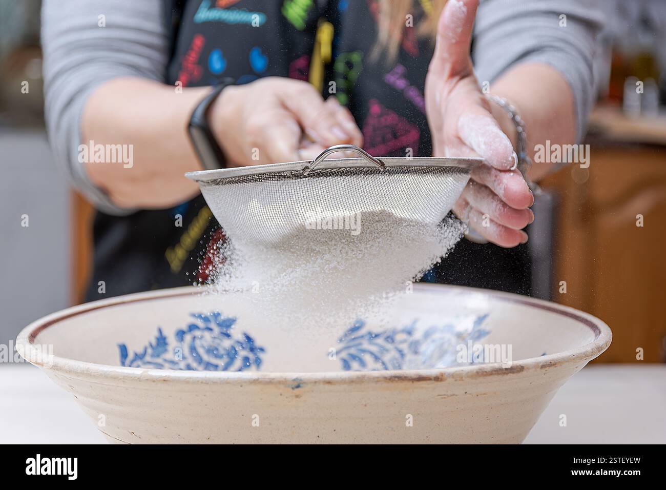 Sifting flour with a sieve over a bowl using your hands Stock Photo - Alamy