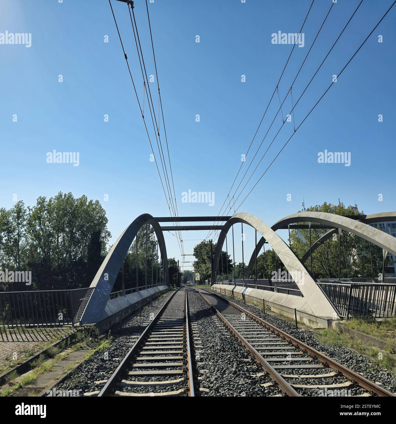 The train tracks under a modern arch bridge evoke awe, showcasing ...