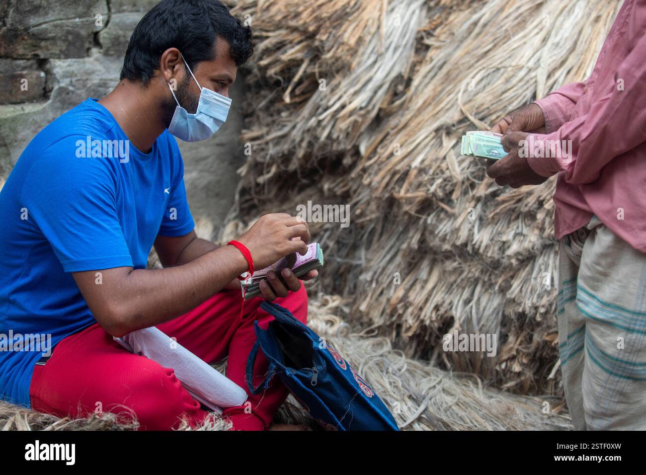 A trader hands payment to a farmer after purchasing raw jute at the ...