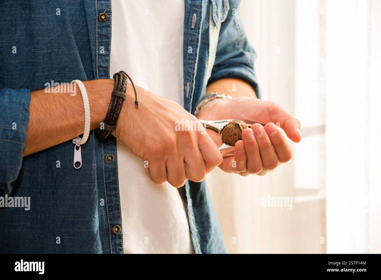 Hands of young man cracking nut with nutcracker at home. Healthy diet ...