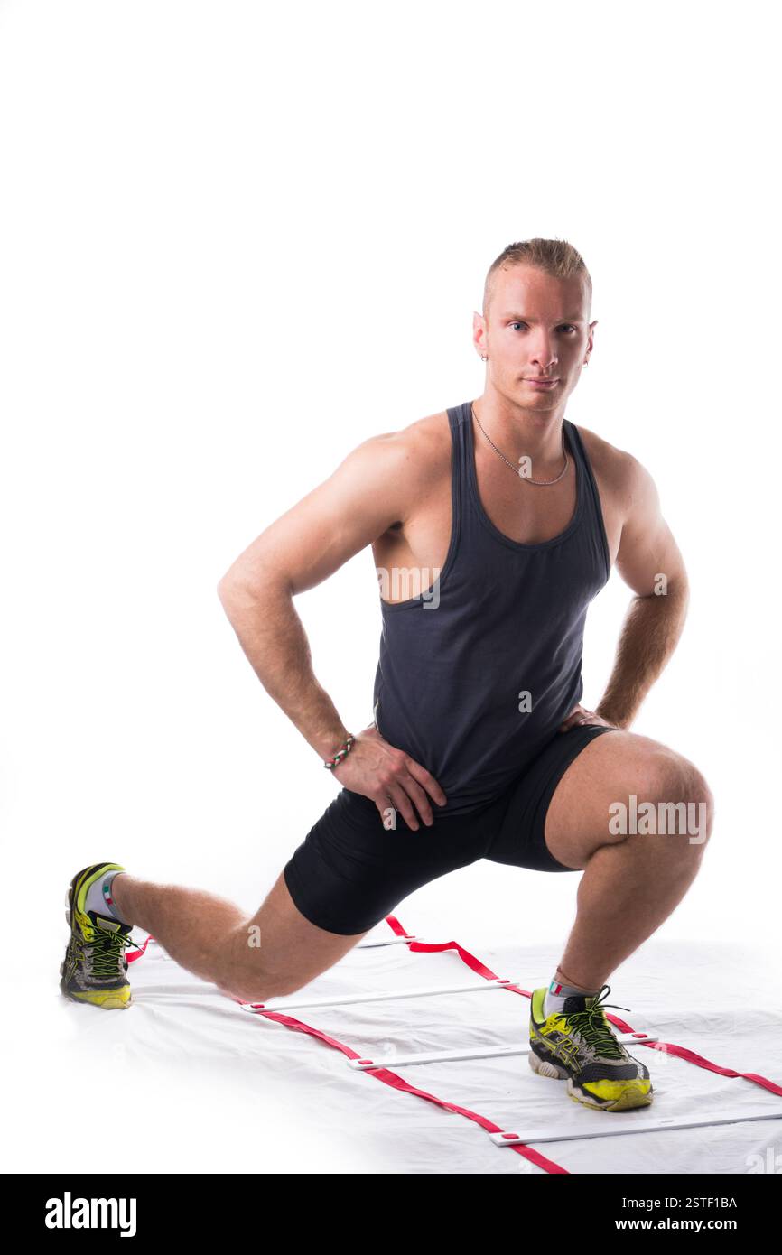 Attractive athletic young man working out with agility ladder on white ...