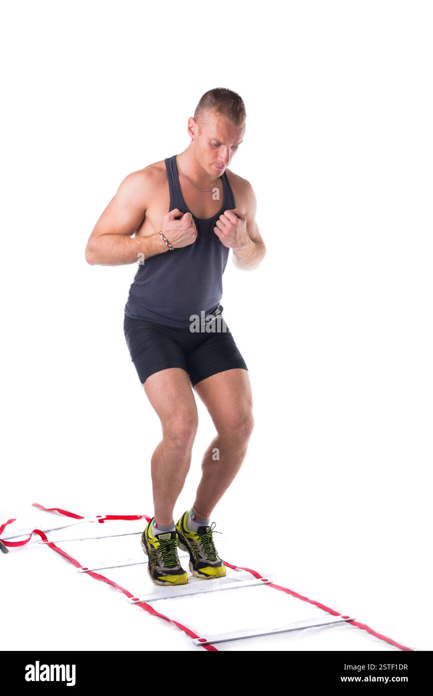 Attractive athletic young man working out with agility ladder on white ...