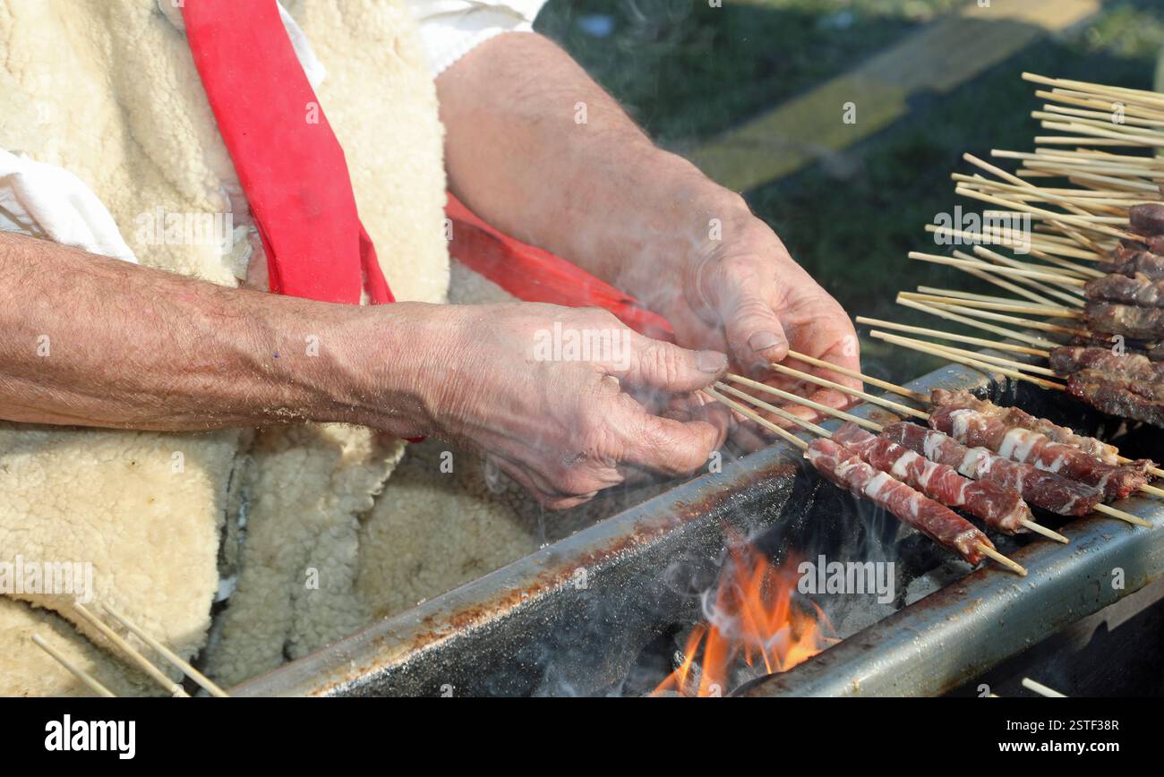 Large hands of the cook, the flare of the fire, and the meat skewers ...