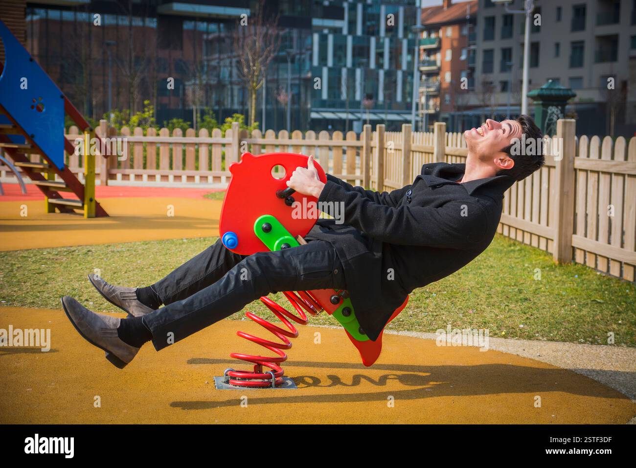 Young man reliving his childhood plying in a childrens playground ...