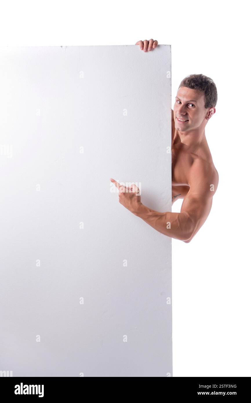 Strong muscular young man behind a blank vertical white banner looking ...