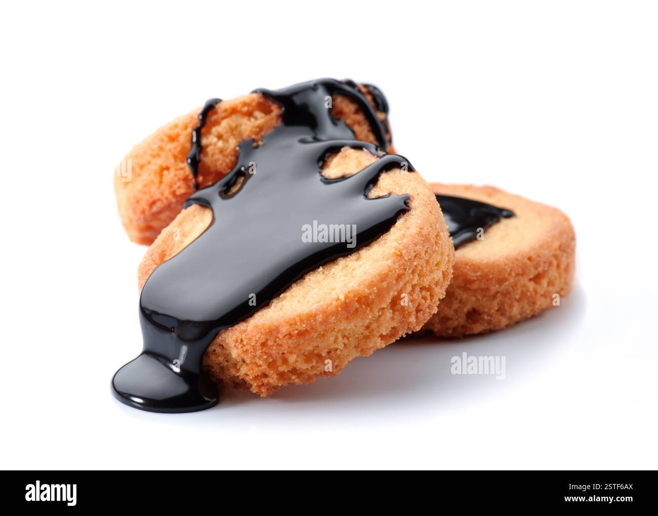 Two golden cookies are layered with a thick drizzle of black chocolate ...