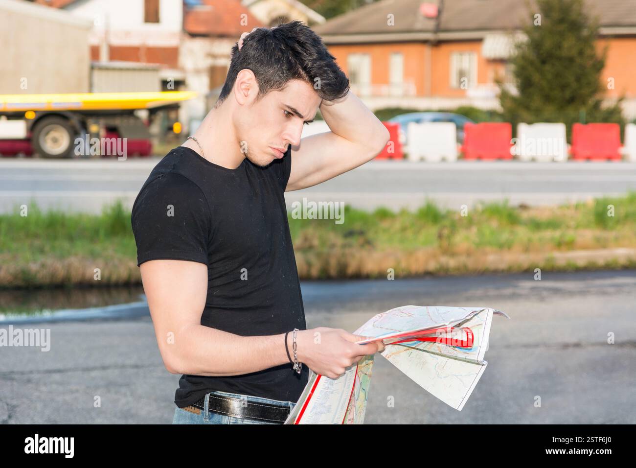 Young man searching for a location from printed map Stock Photo - Alamy