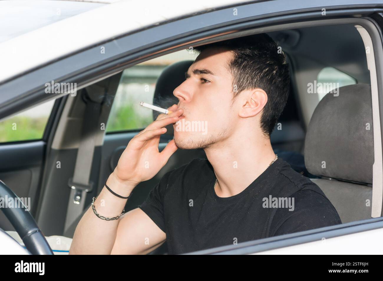Young Man smoking cigarette while Driving Stock Photo - Alamy
