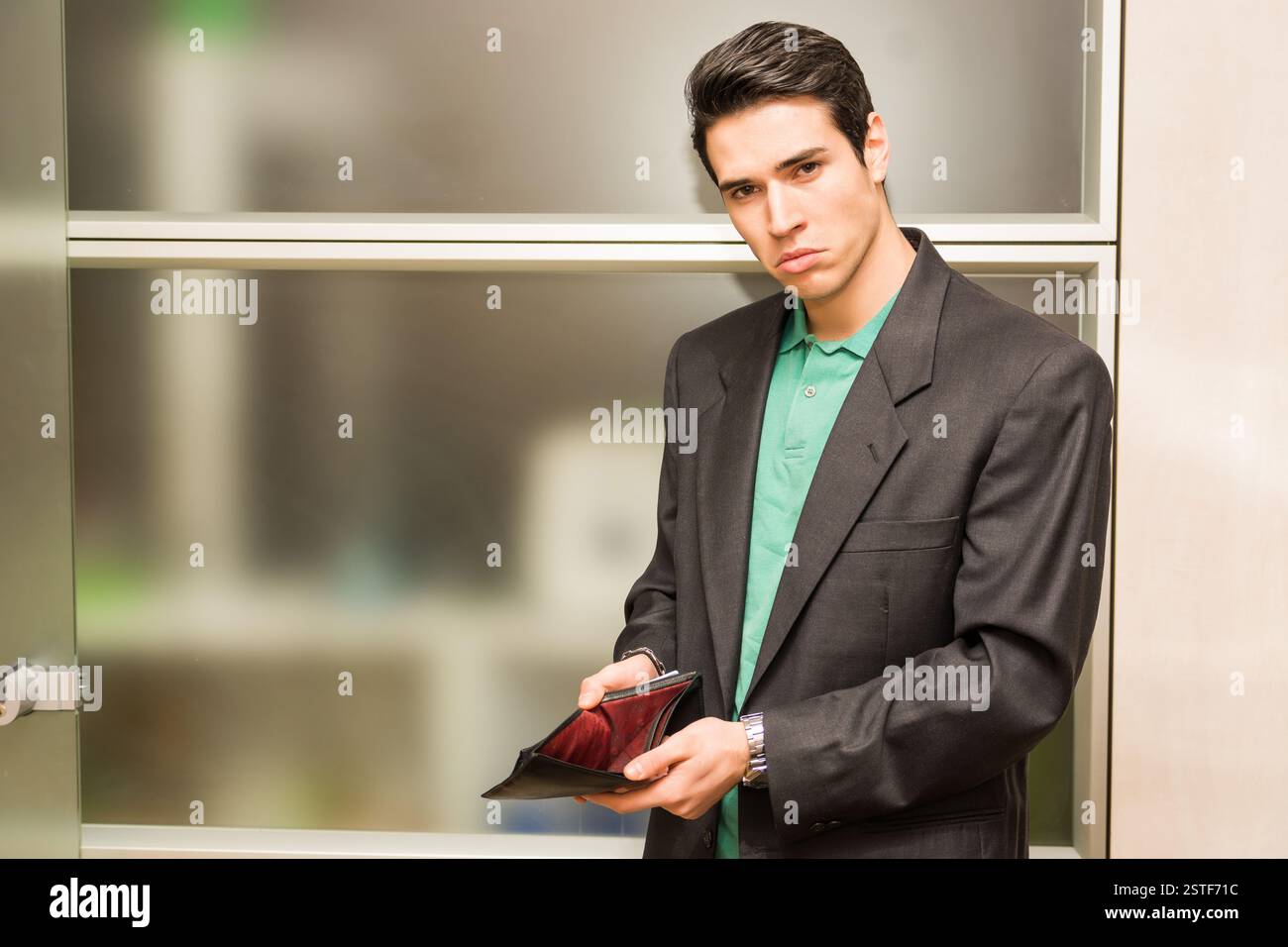 Sad looking young business man in office showing empty wallet hi-res ...