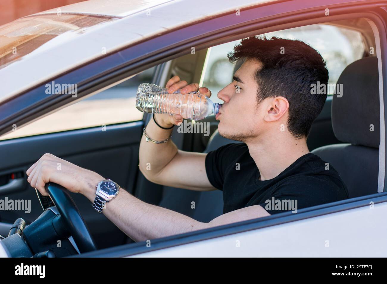 Young man driving car and drinking water from bottle Stock Photo - Alamy