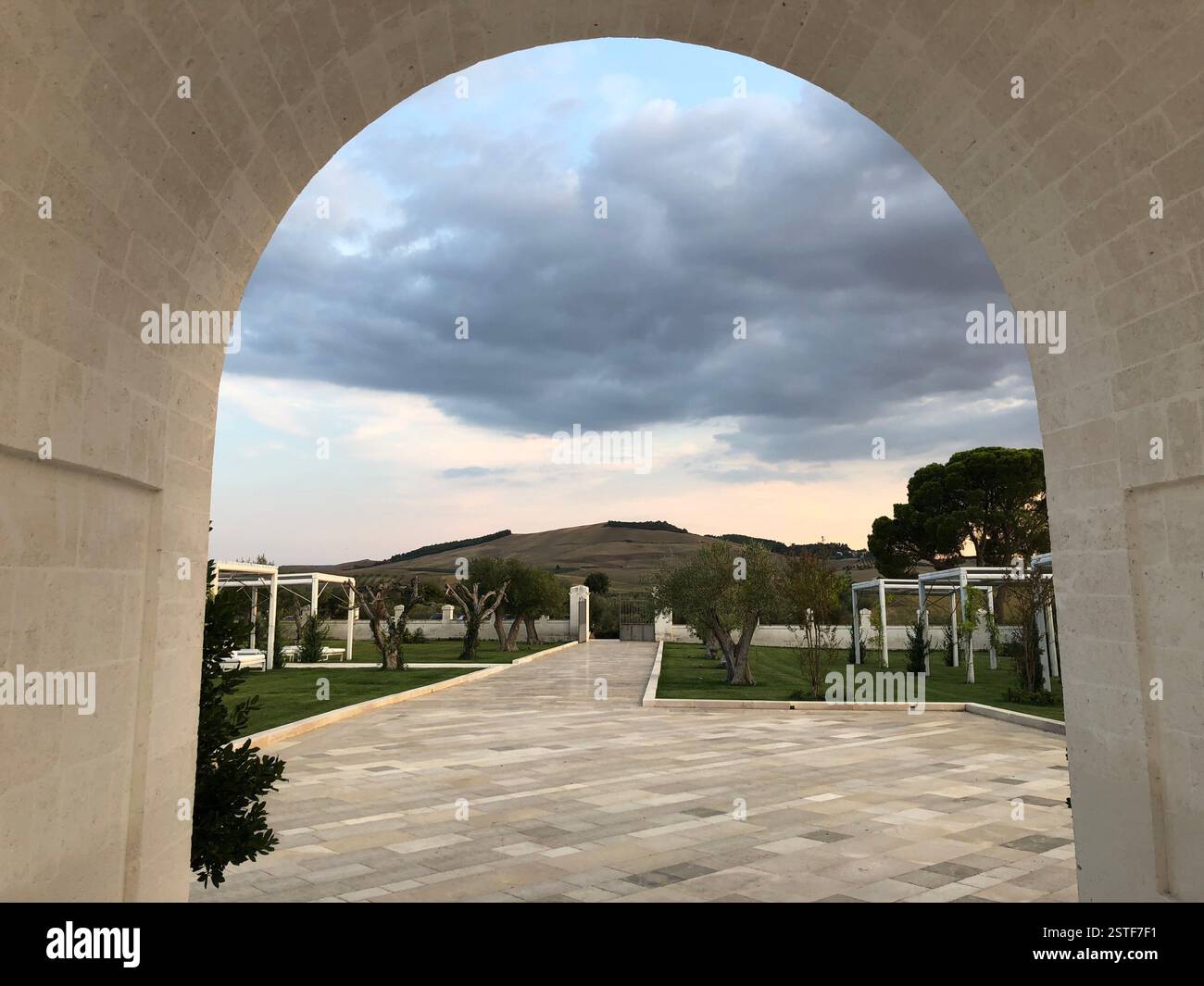 Framed by an elegant arch, an expansive view reveals lush greenery ...